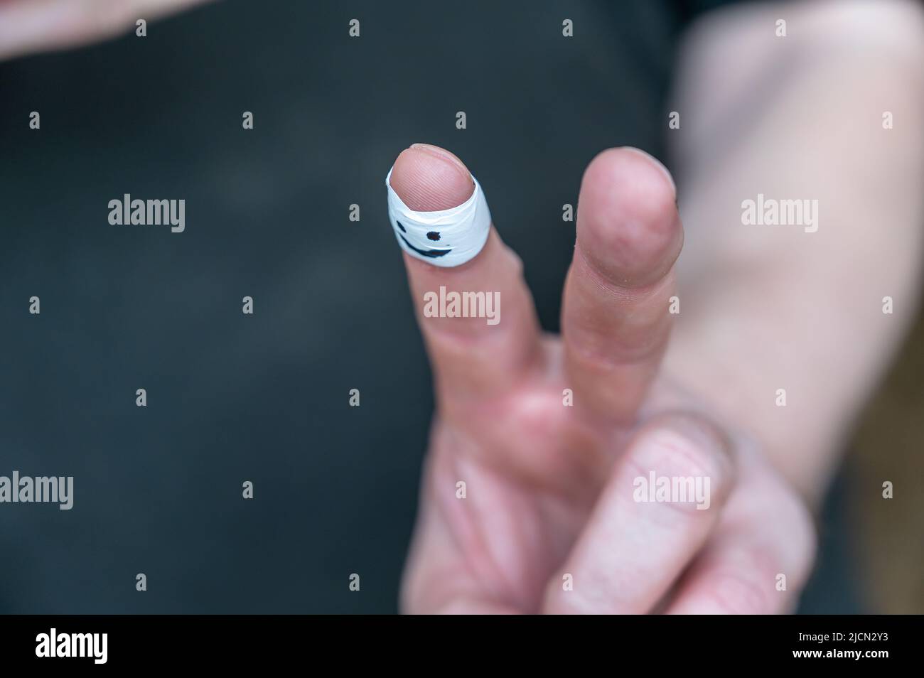 Close-up of a man's hand showing a gesture of victory. White armband on ...