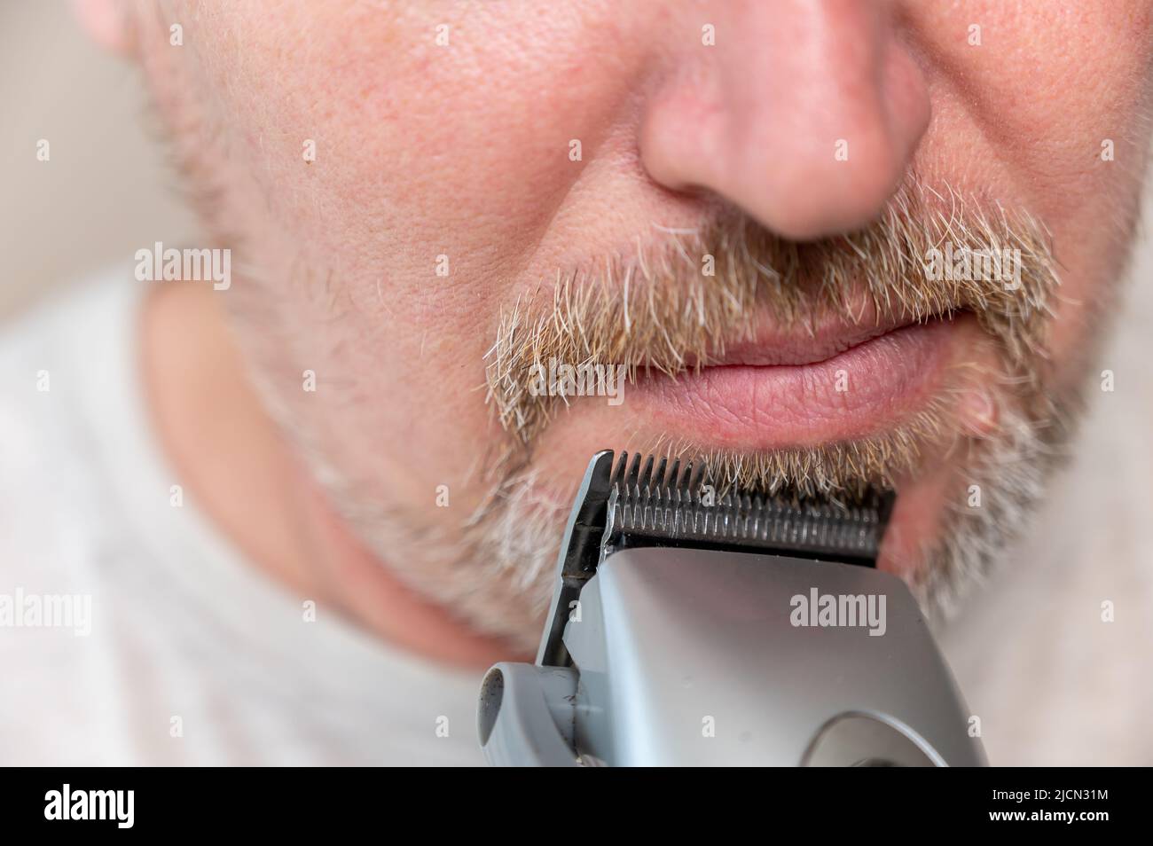A mature man shaving. The bottom of a man's face. Man cuts facial hair ...