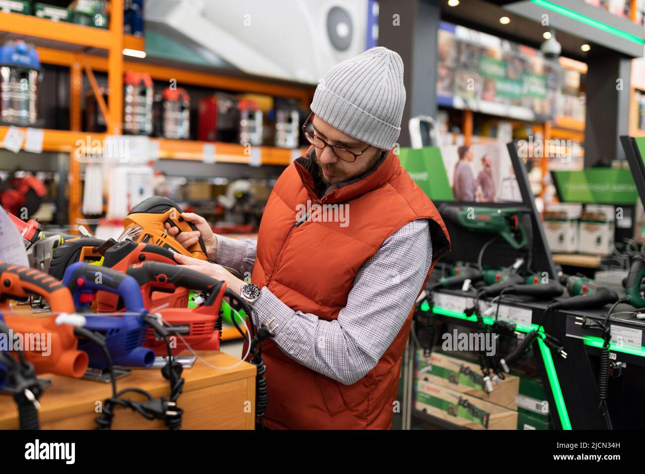 a man in a hardware store chooses a jigsaw Stock Photo - Alamy