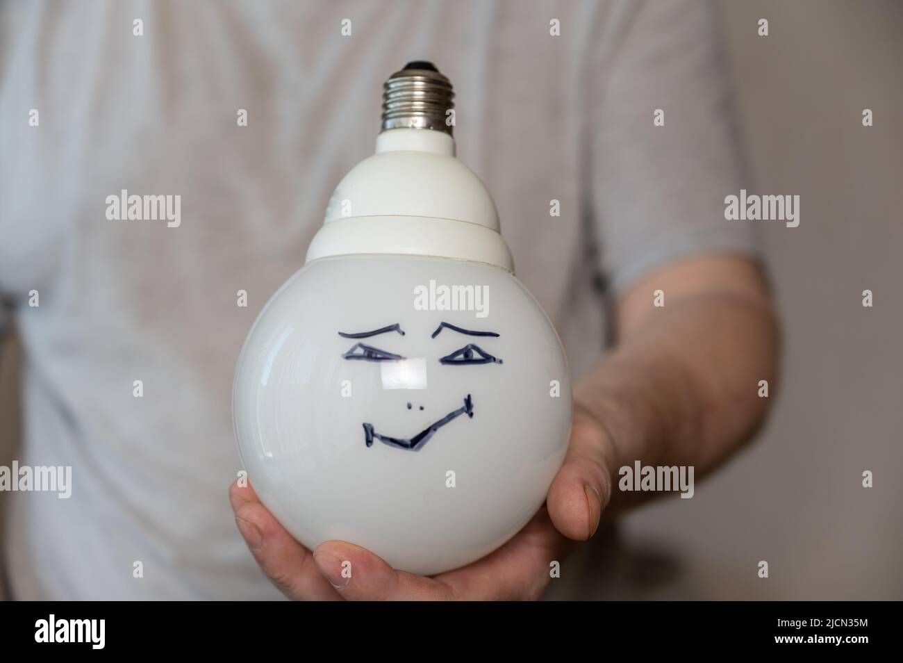 A middle-aged man is holding an electric lamp with his face painted on ...