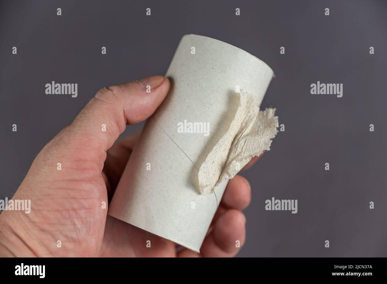 A middle-aged man is holding an empty sleeve of taulet paper. A ...