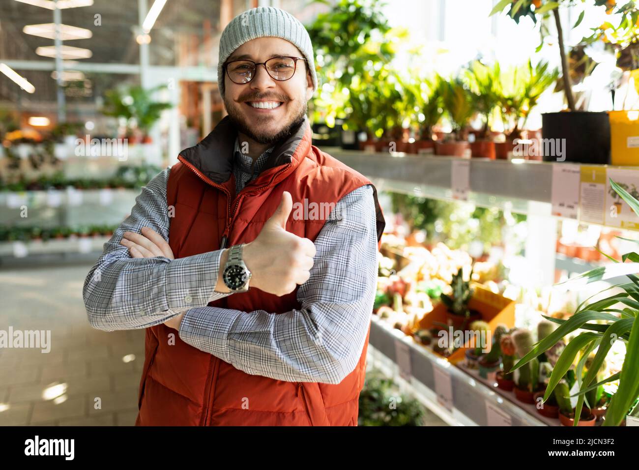 a sales assistant in a gardening goods store looks at the camera with a ...