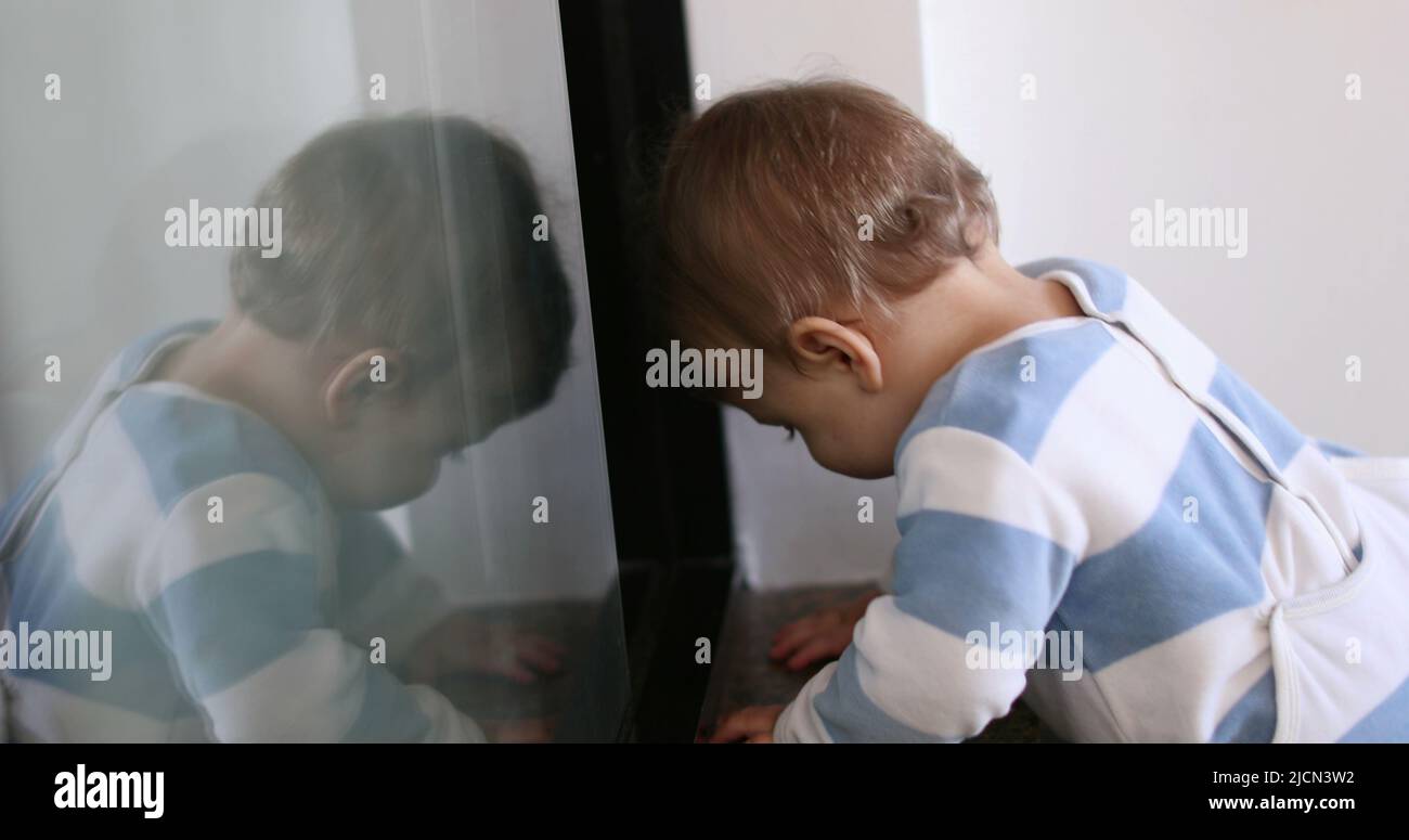 Cute baby toddler standing up by home window. Adorable infant boy child ...