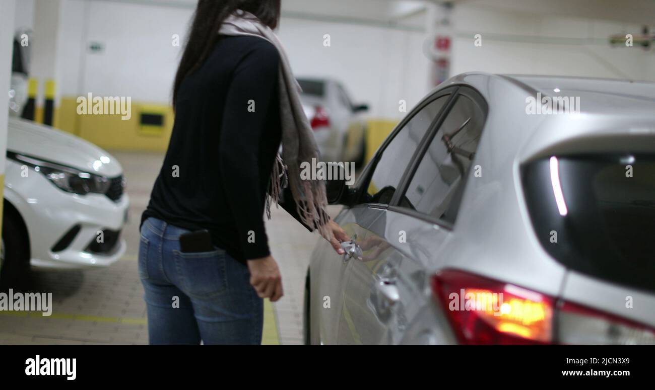 Female driver opening car door and getting inside vehicle at parking ...