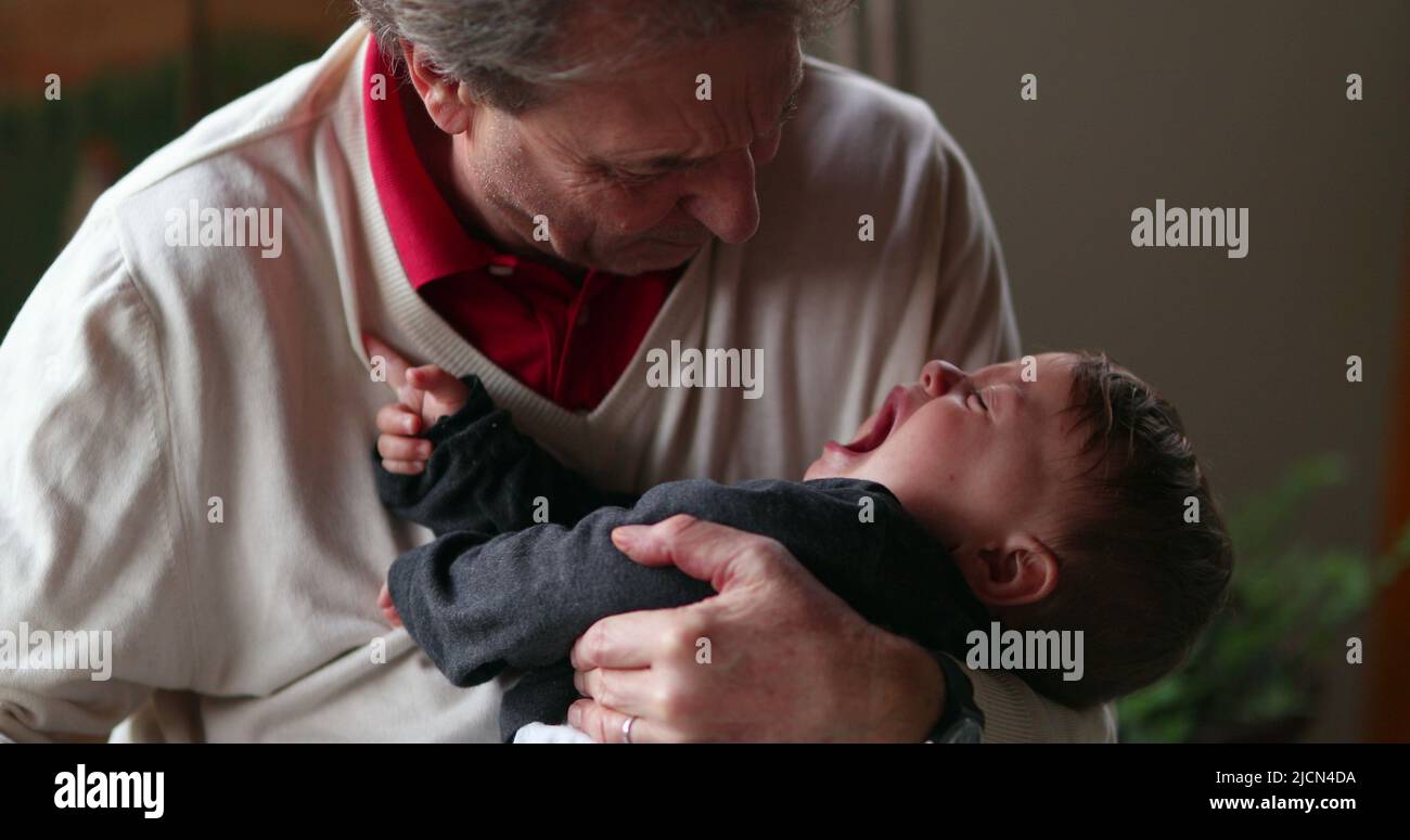 Upset baby with grand-father. Grand-parent consoling crying grand-child ...