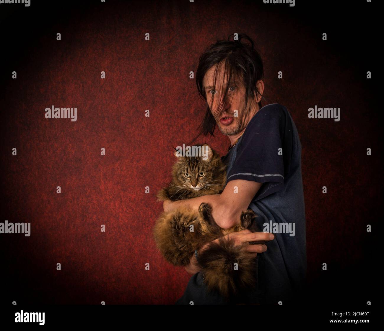 Junkie man with young tabby cat with big green eyes near red wall Stock ...