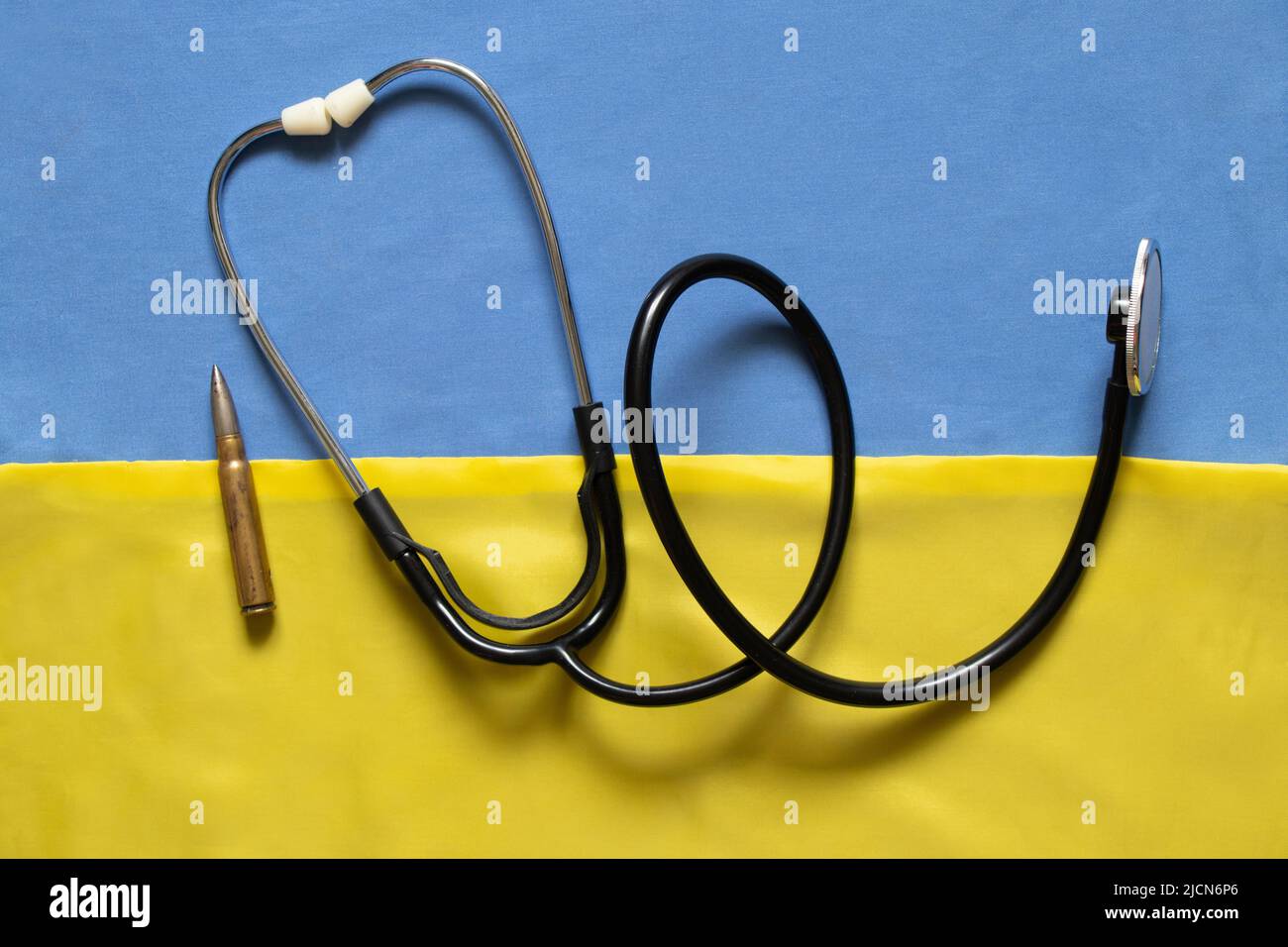 A stethoscope and a bullet lie on the national flag of Ukraine yellow ...