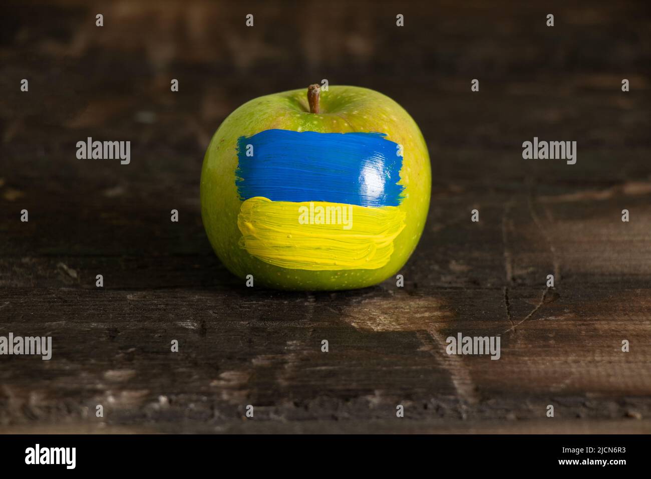 A green apple with the national flag of Ukraine in yellow and blue lies ...