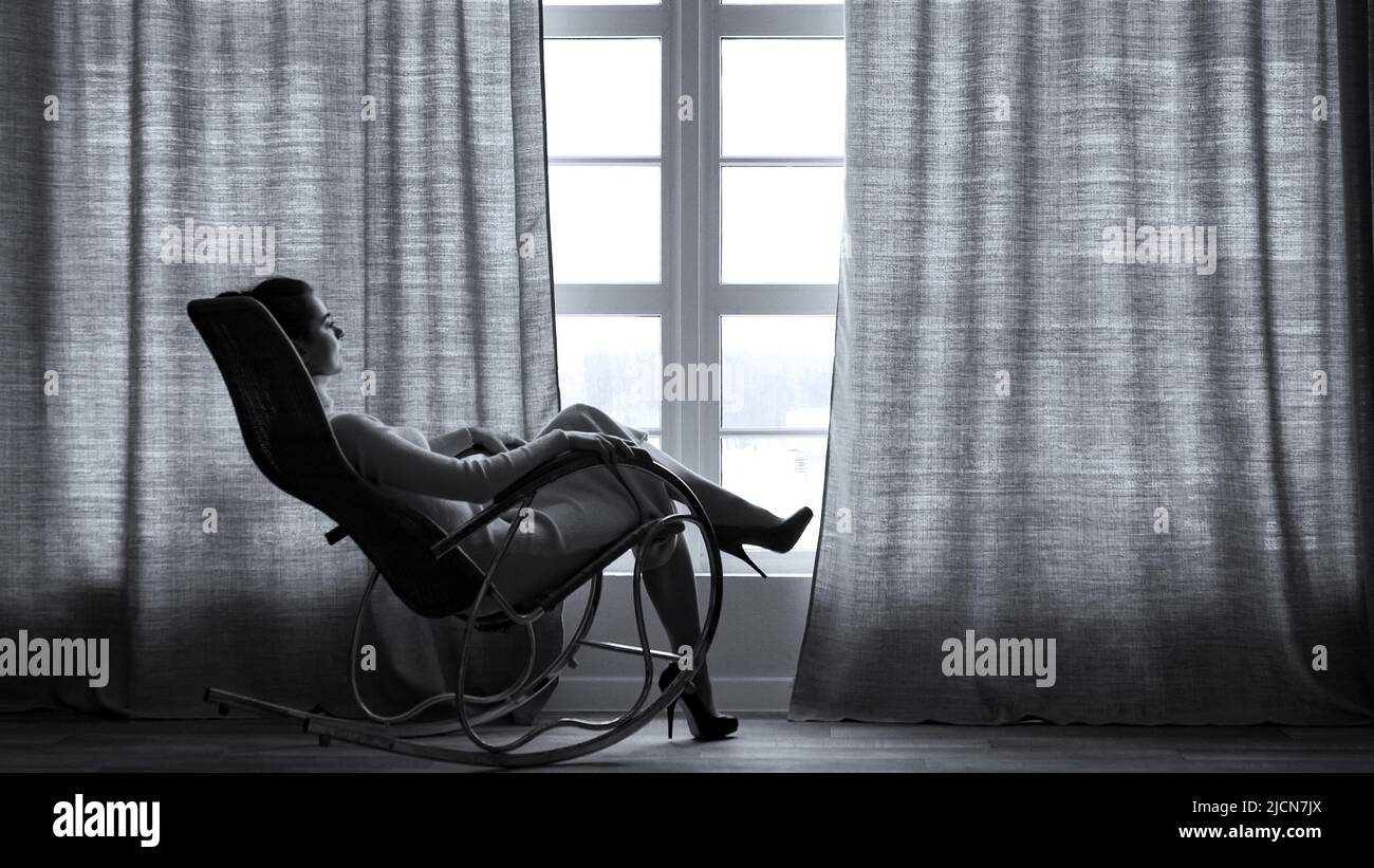 Woman sitting in a rocking chair and looking in a window Stock Photo ...
