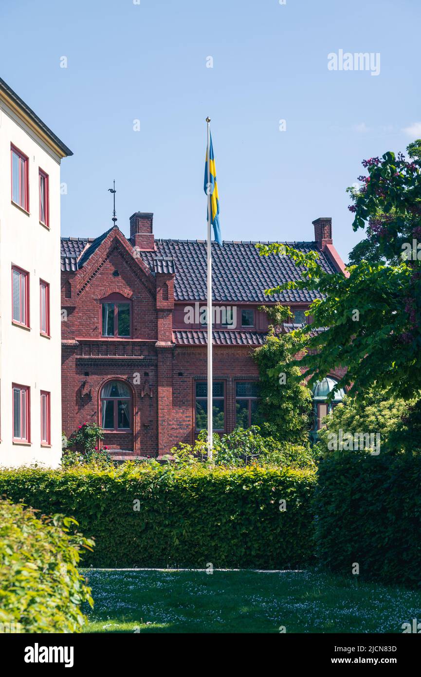 Swedish flag on flag pole in front of red brick building in summer time ...