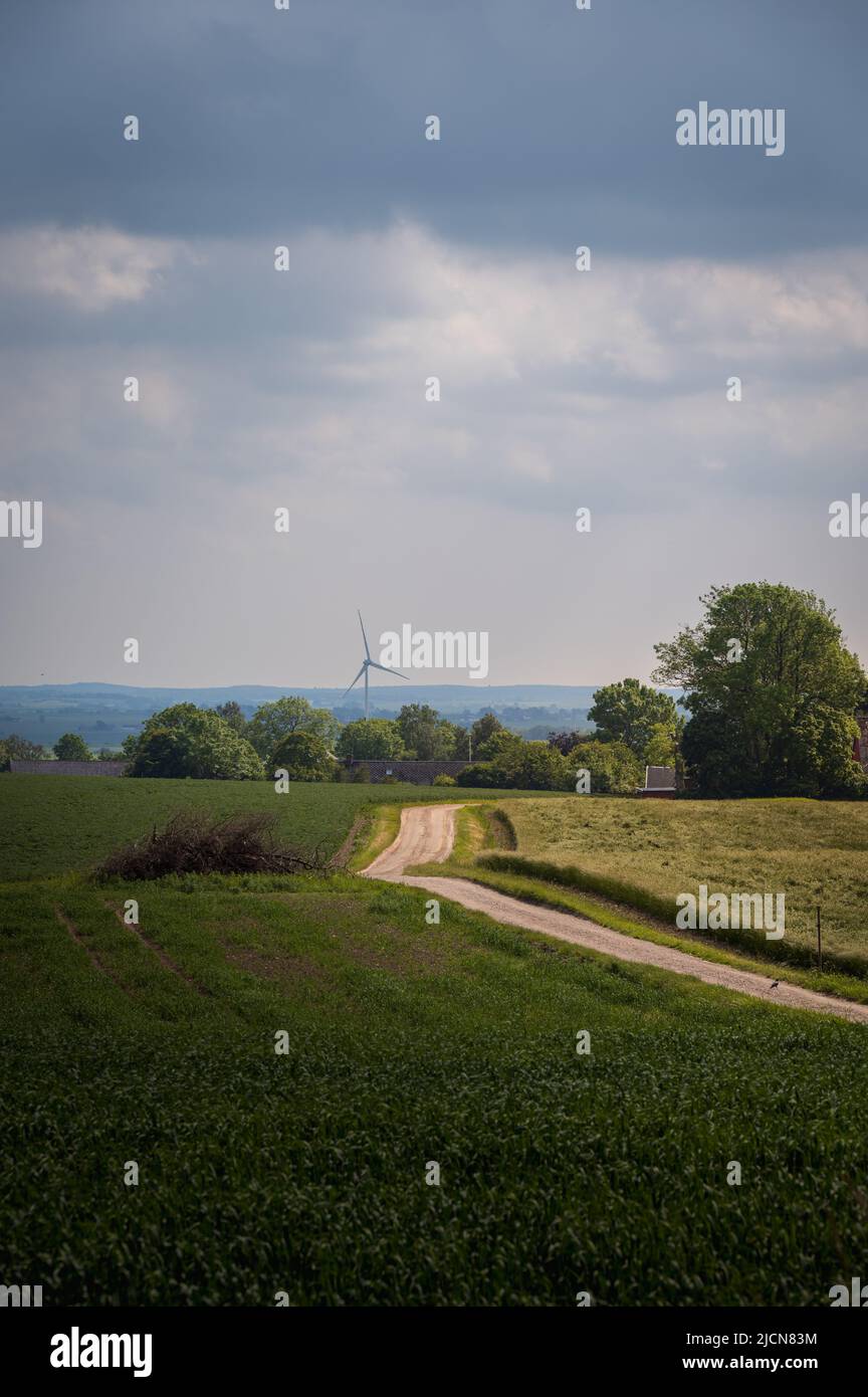 Rural gravel road through farm fields towards wind power plant in Skåne ...