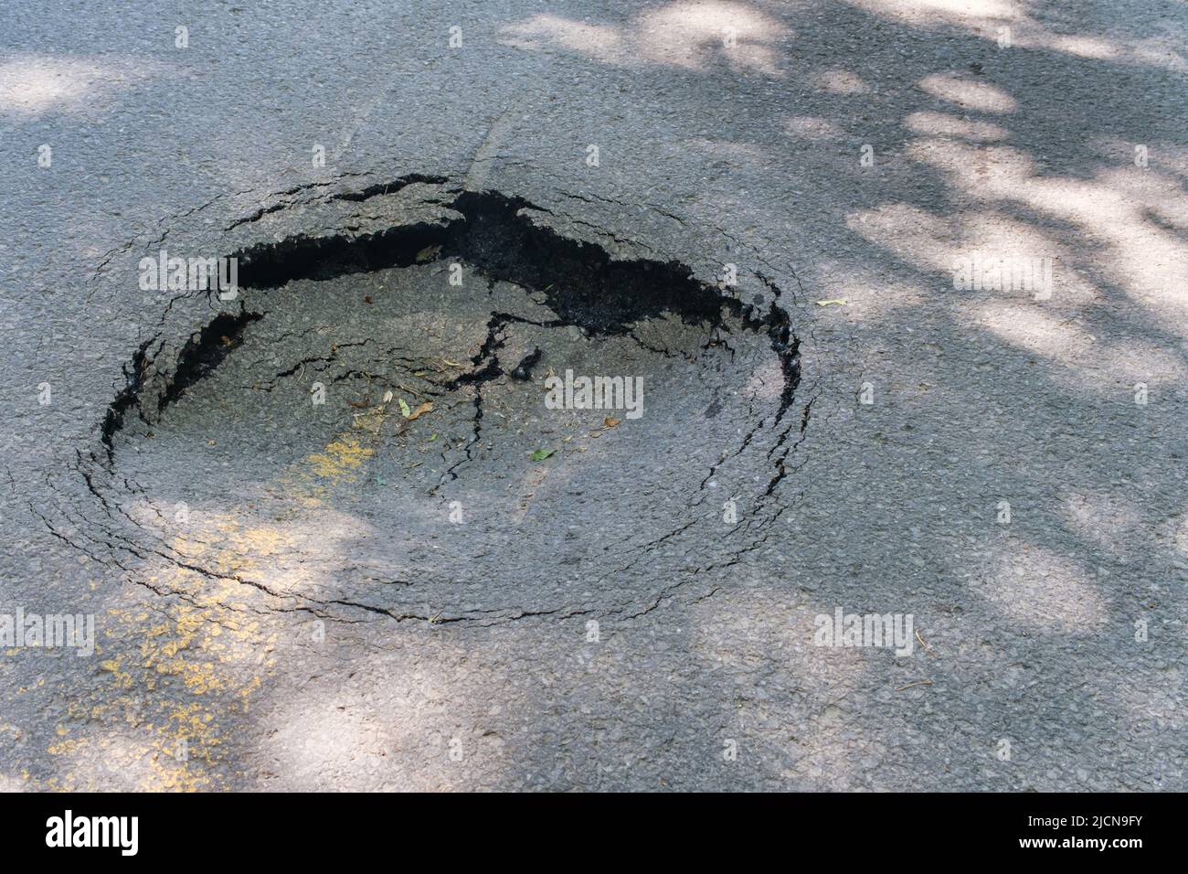 Large rounded pothole in Montreal with traffic cone Stock Photo - Alamy