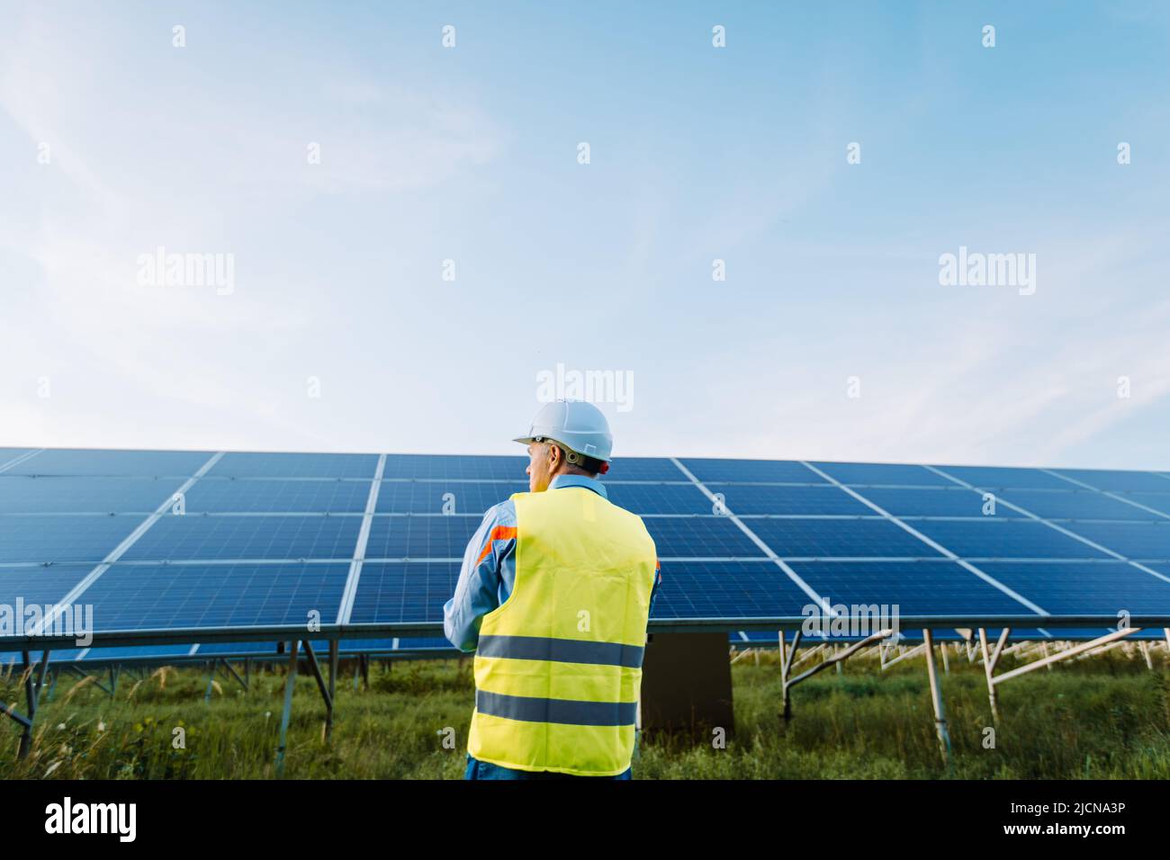 Rear view of worker at solar farm. Solar photovoltaic panels. Eco ...