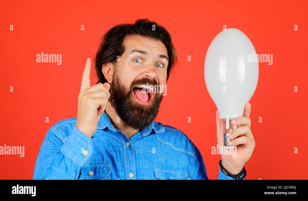 Good idea. Happy man with light bulb. Bearded male with lamp pointing ...