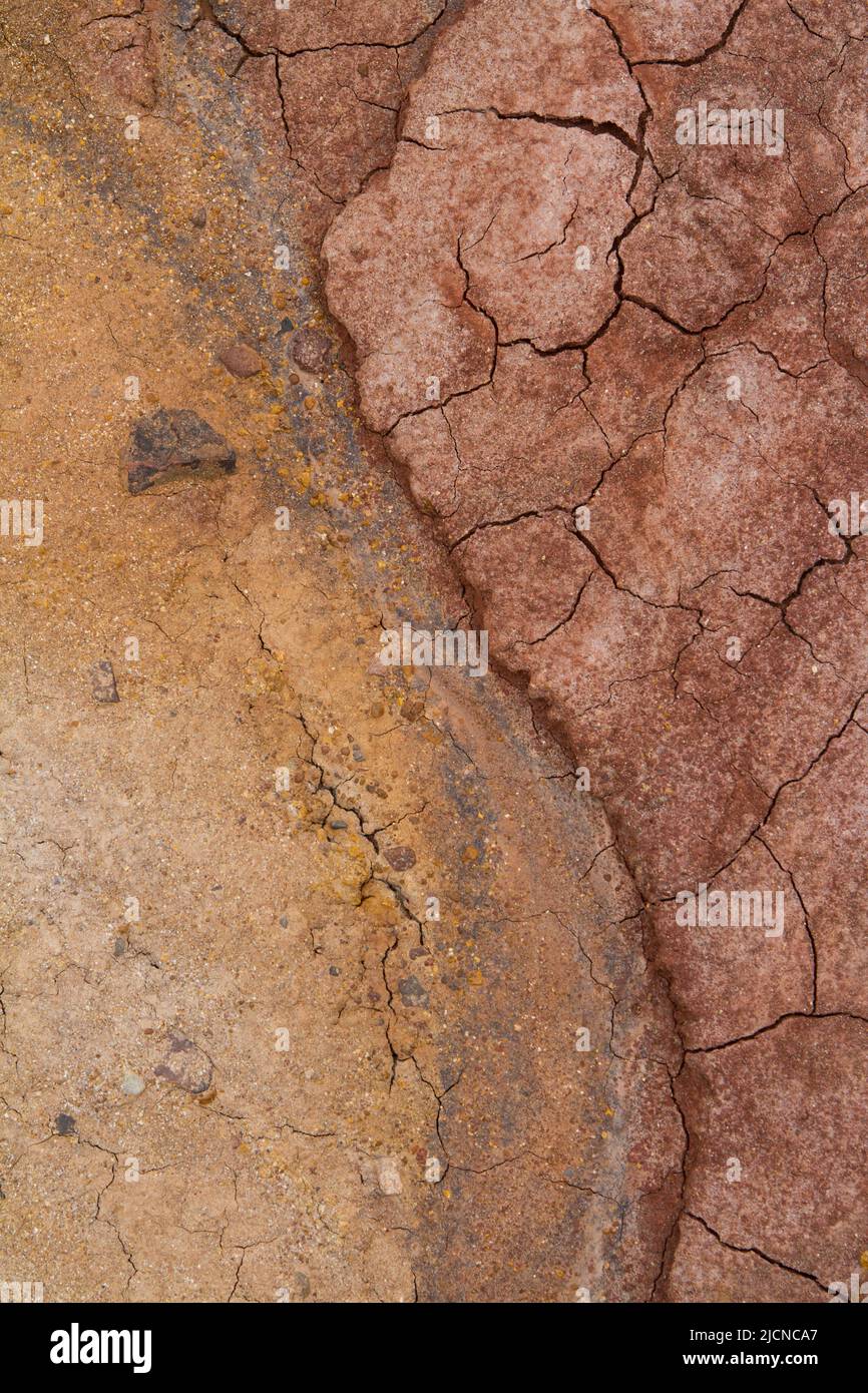 Closeup photograph of colorful dried earth in shades of gold, red, and ...