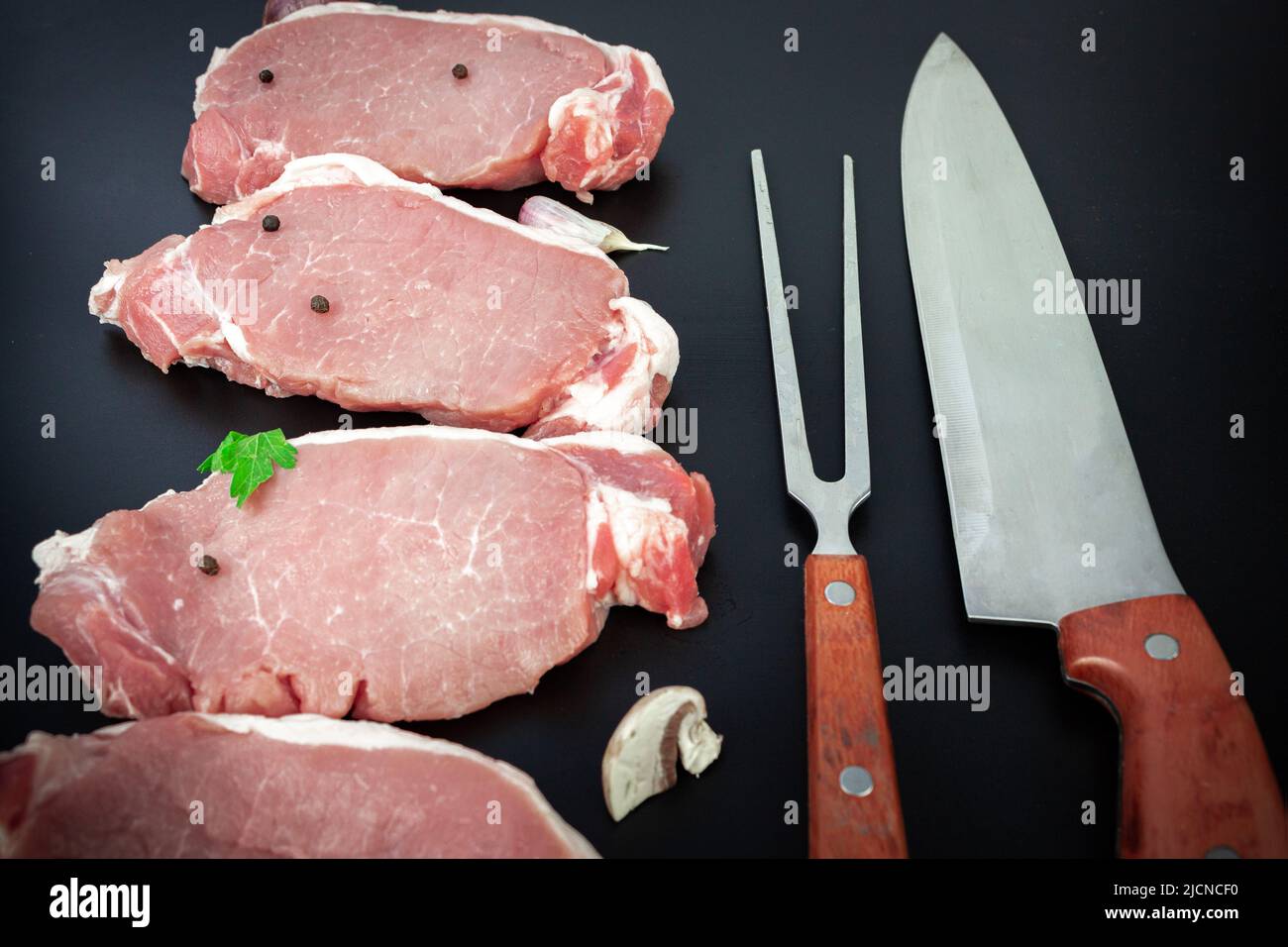 Pieces of raw roast beef meat with ingredients and meat knife and meat ...