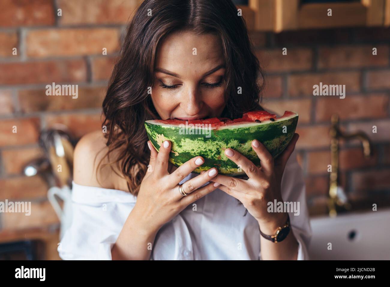 Woman at home eating watermelon in the kitchen Stock Photo - Alamy