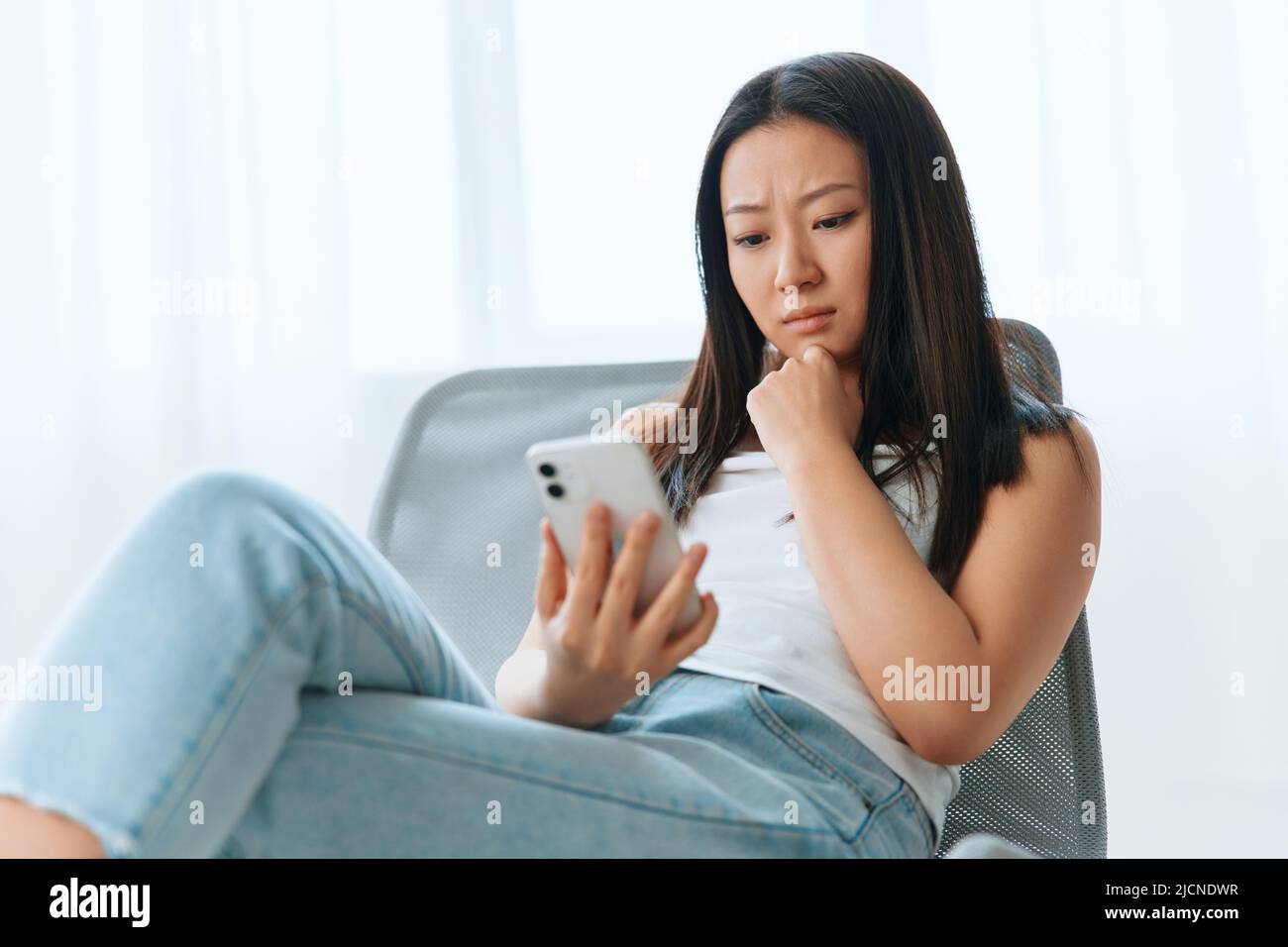 Upset confused tanned lovely young Asian woman read shocked message ...