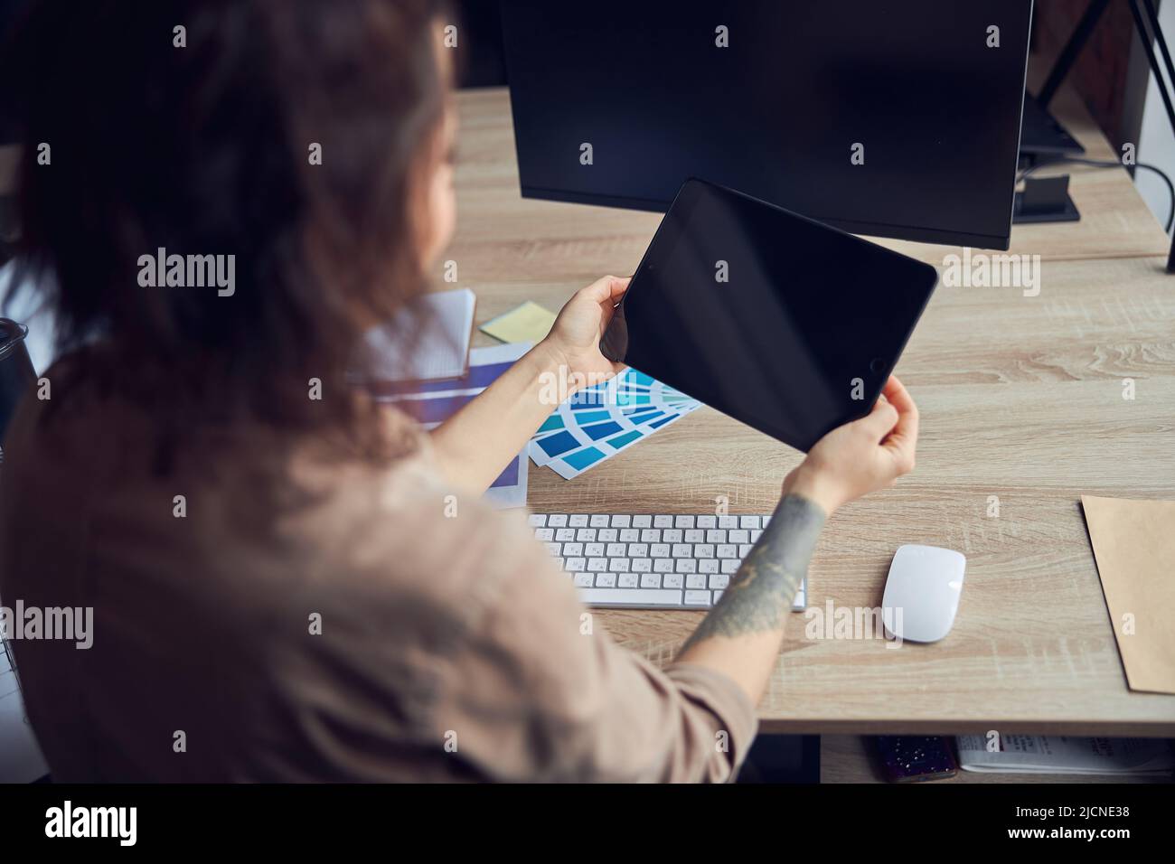 Rear view of female interior designer holding tablet pc with blank ...