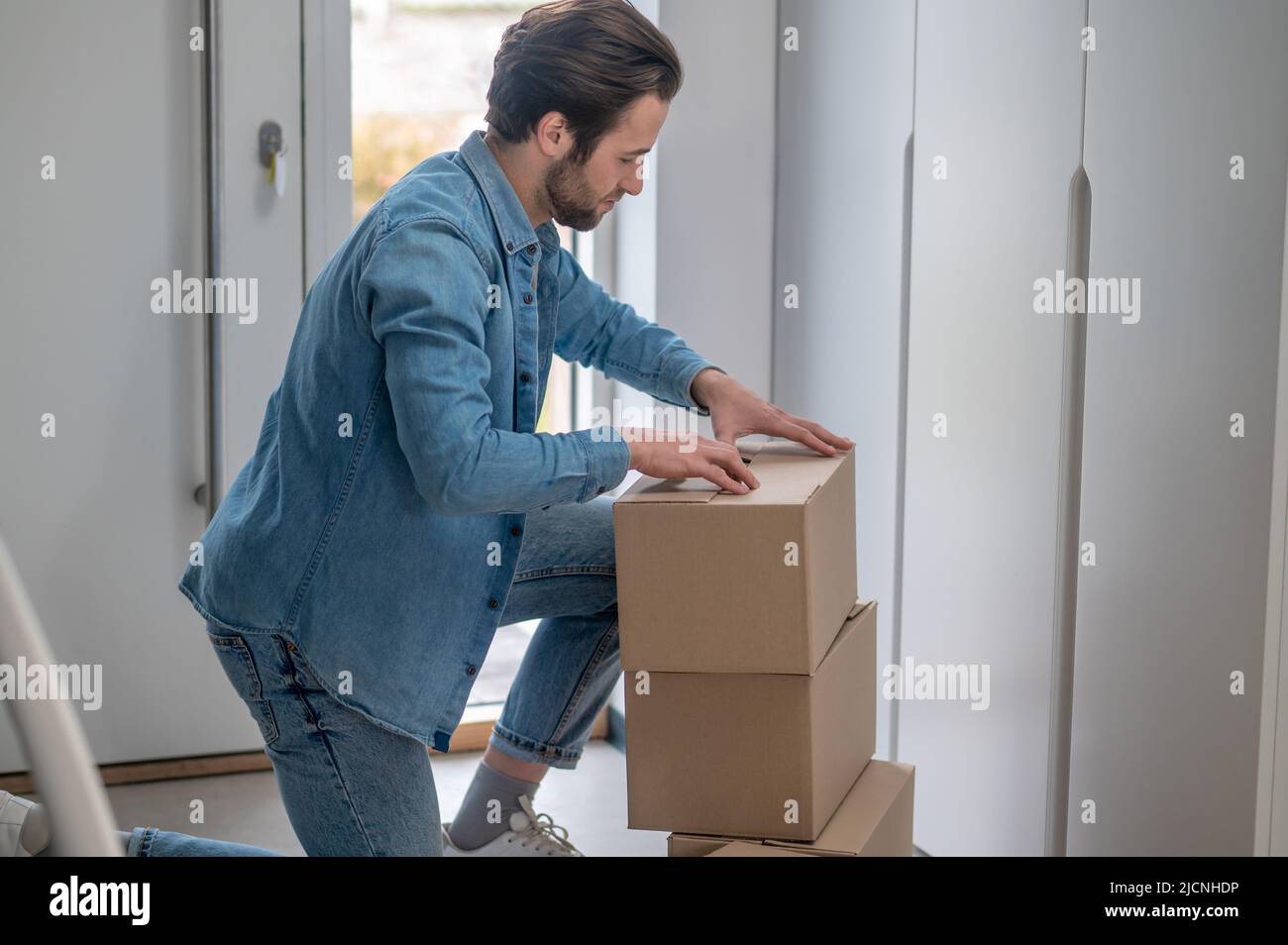 Man sideways to camera crouched near boxes Stock Photo - Alamy