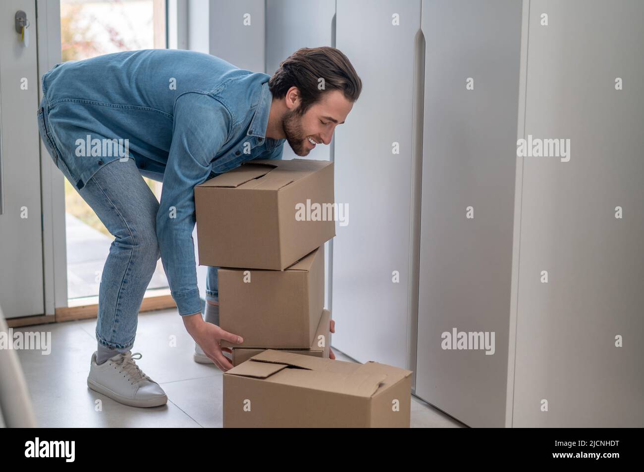 Man sideways to camera leaning over boxes Stock Photo - Alamy
