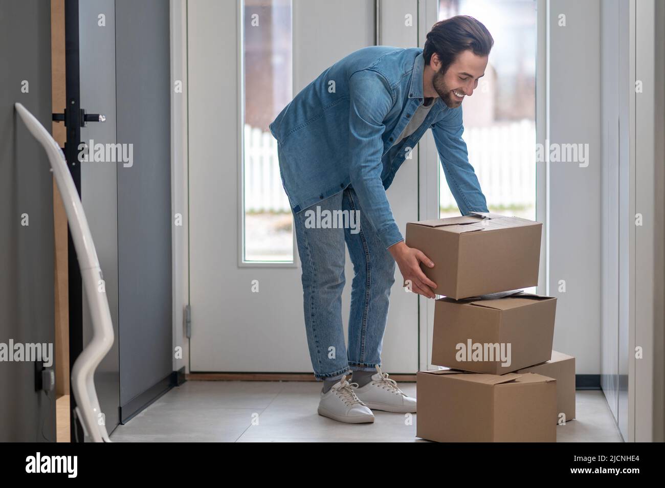 Smiling man standing bent over stacking boxes Stock Photo - Alamy