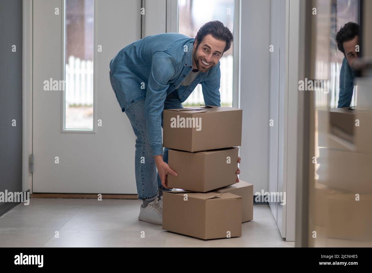 Man bending over with boxes smiling to side Stock Photo - Alamy