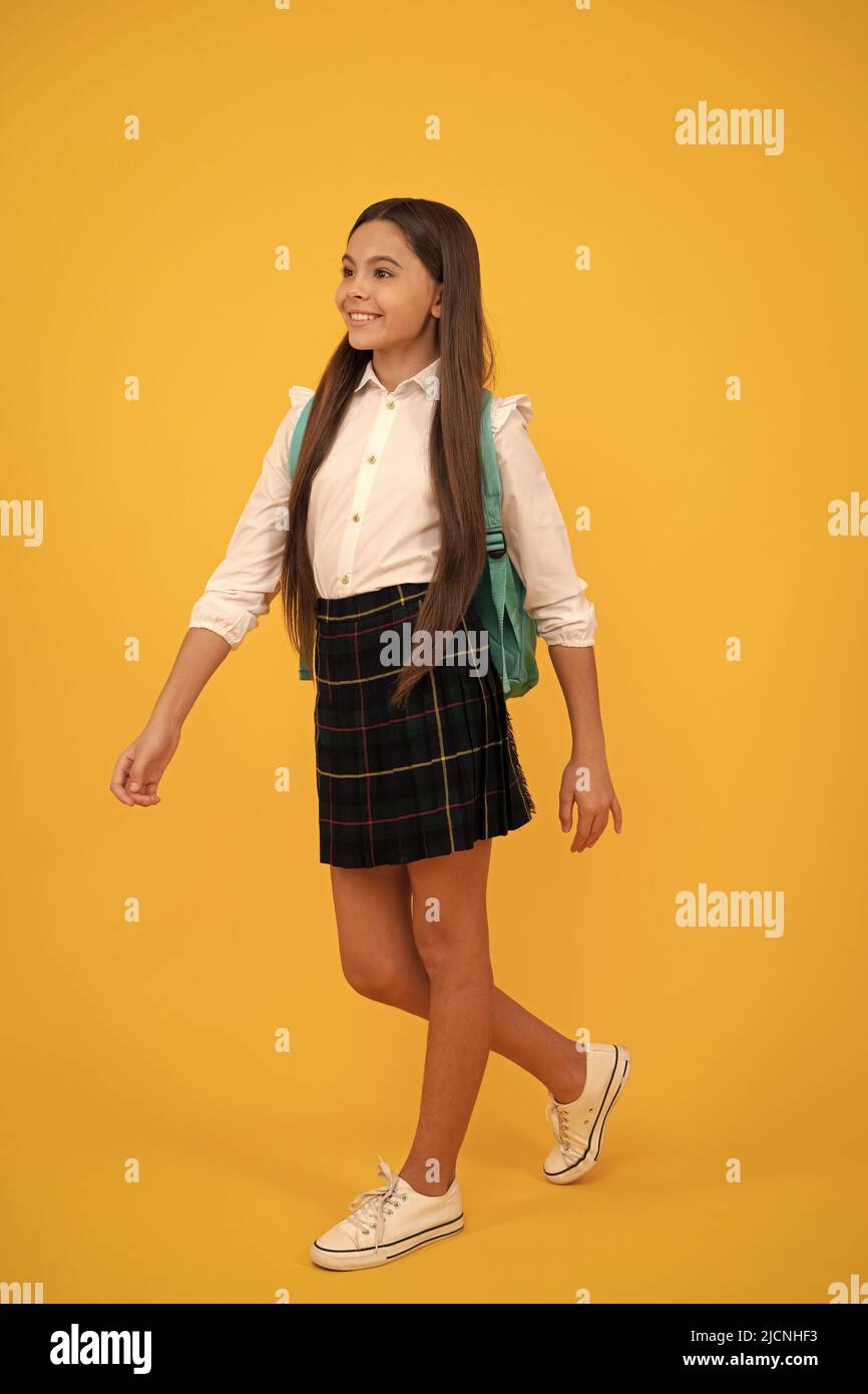 happy teen girl in school uniform full length on yellow background ...