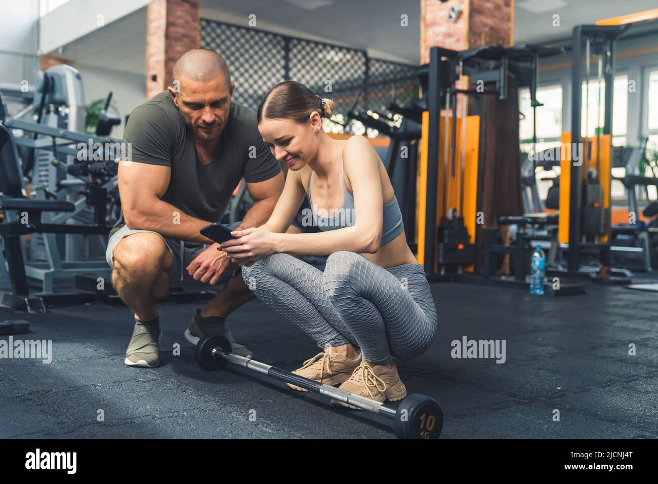 Young modern fashionable caucasian gym girl shows his muscular male ...