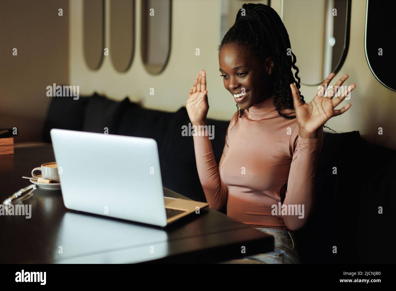 multiracial woman video calling with friends by laptop in coffee shop ...