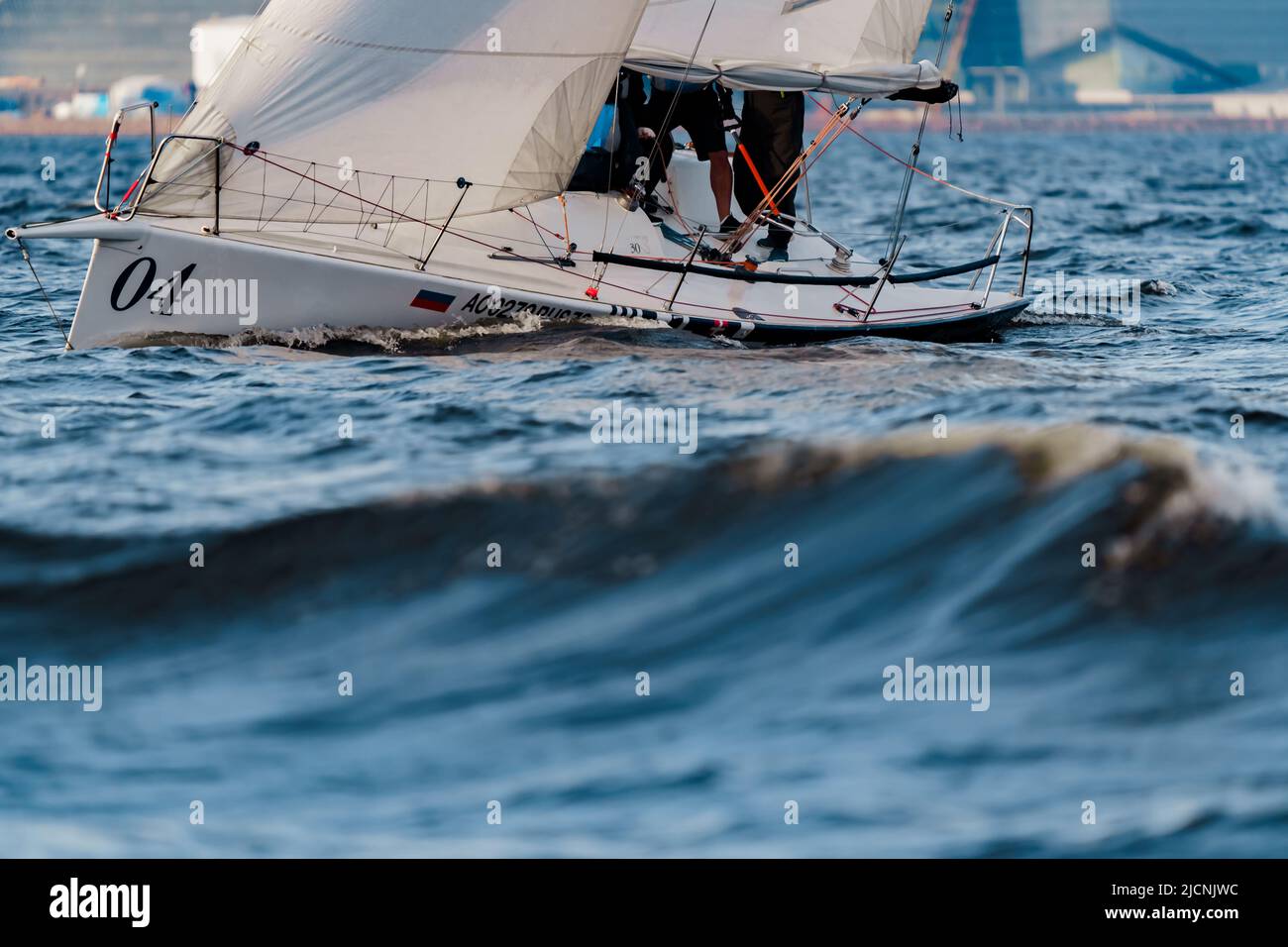 Teamwork in sailing regatta at sunset, sailing yacht in roll, big waves ...