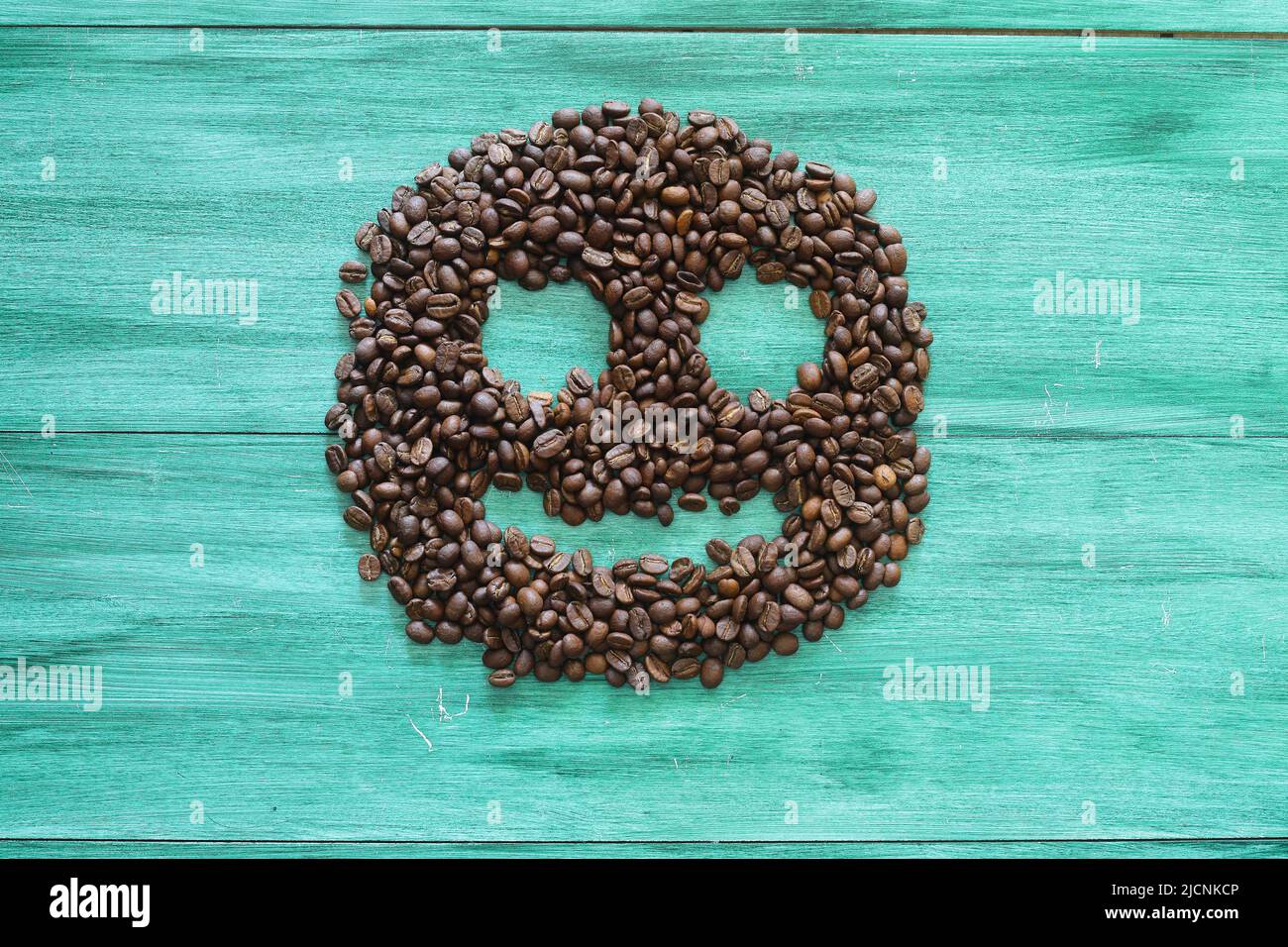 Artificial smiling face made from coffee beans on wooden background ...