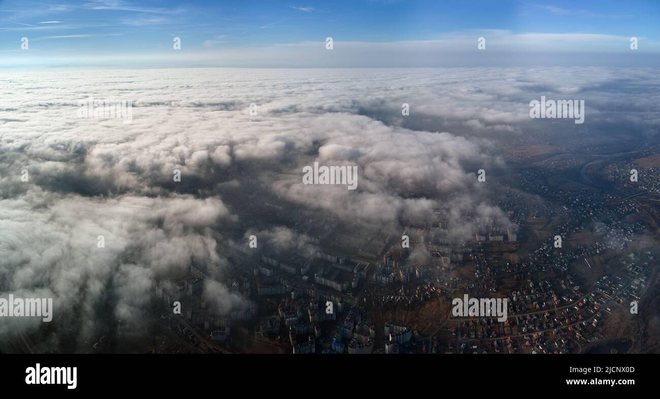 Aerial view from high altitude of distant city covered with puffy ...