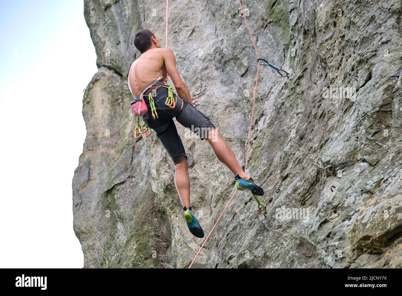Determined climber clambering up steep wall of rocky mountain ...