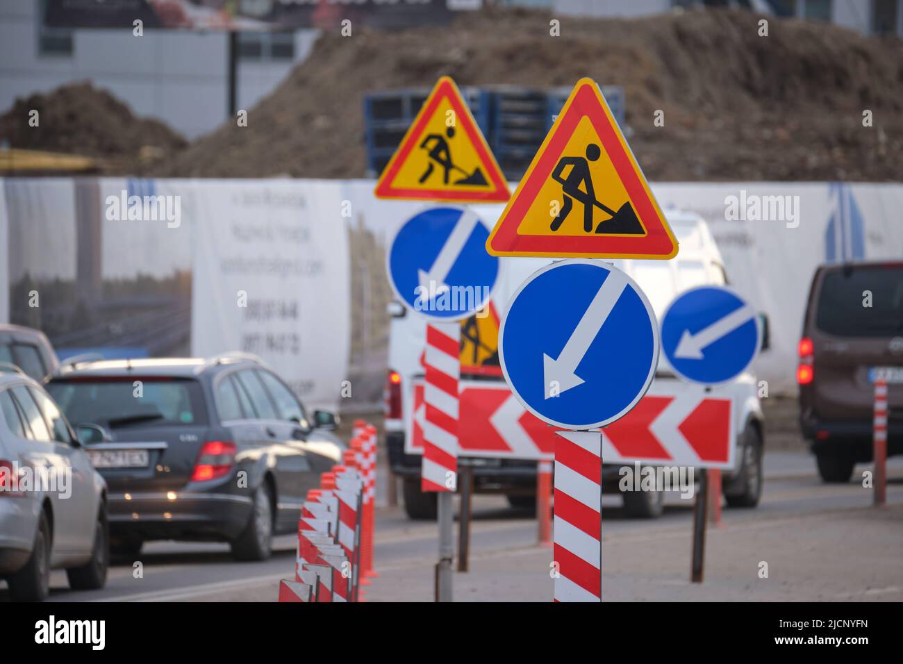 Roadworks warning traffic signs of construction work on city street and slowly moving cars Stock ...