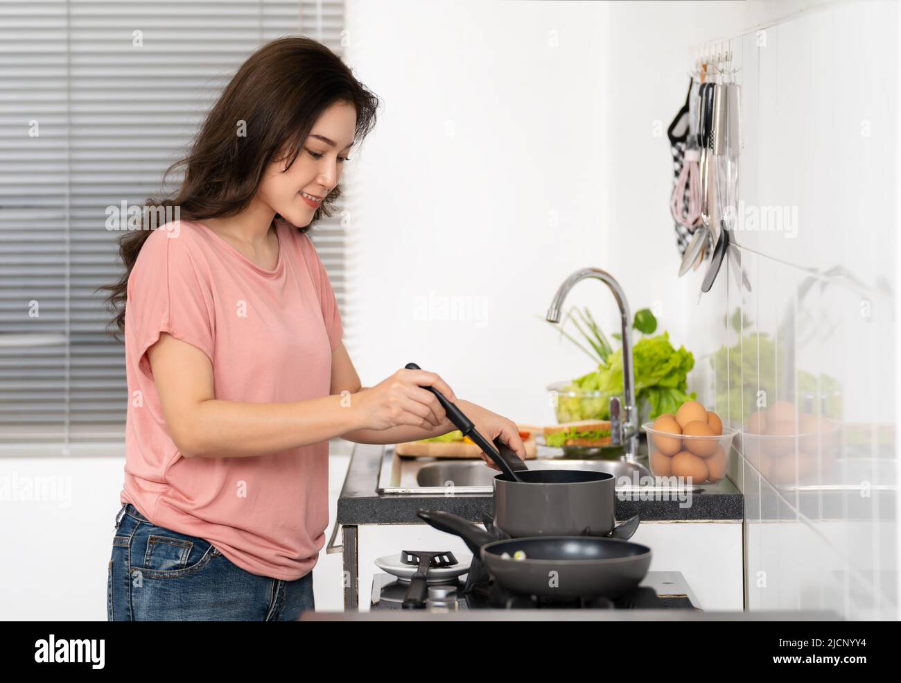 happy young woman cooking and preparing food in the kitchen at home ...