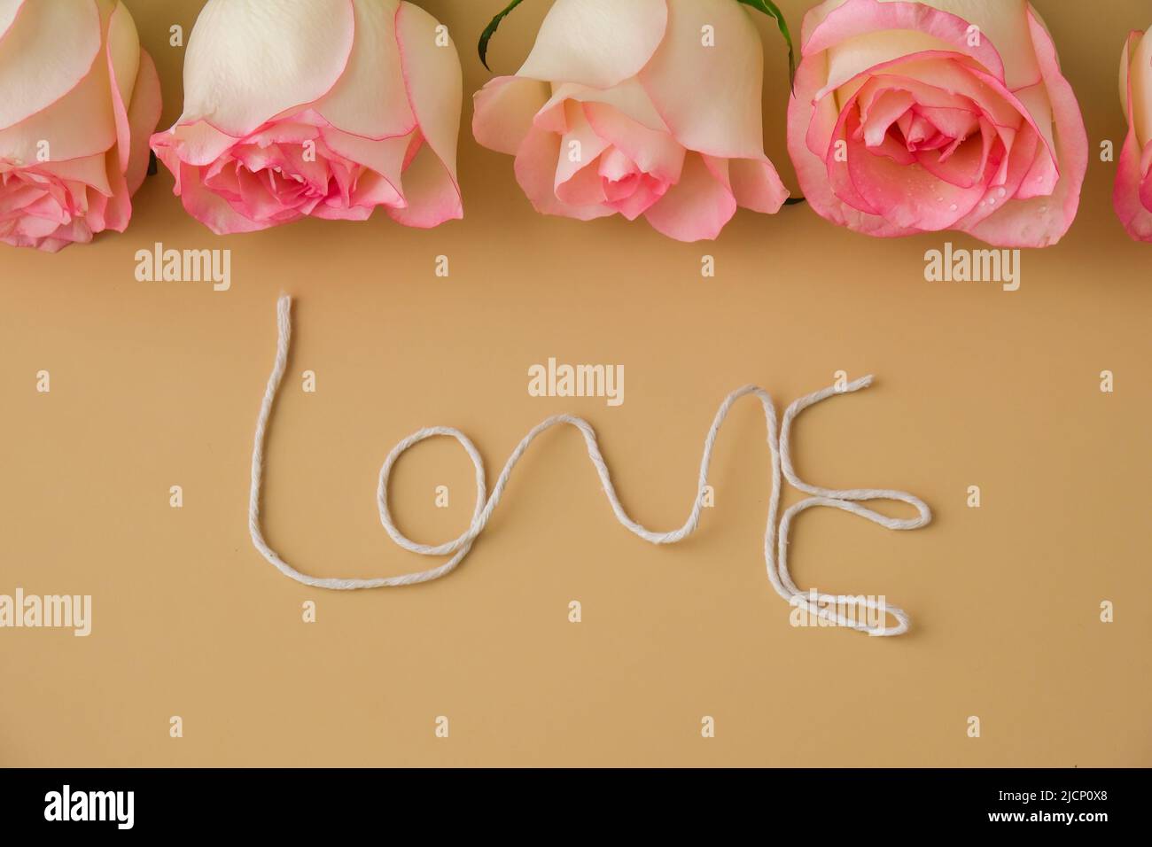 Delicate pink roses on beige background. Word LOVE made of rope ...