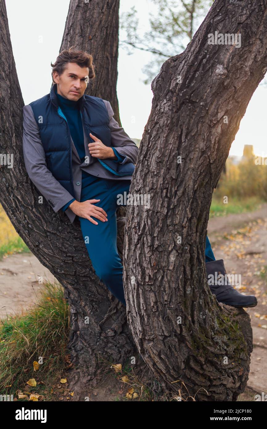 Tall handsome man standing near the tree in autumn forest Stock Photo ...