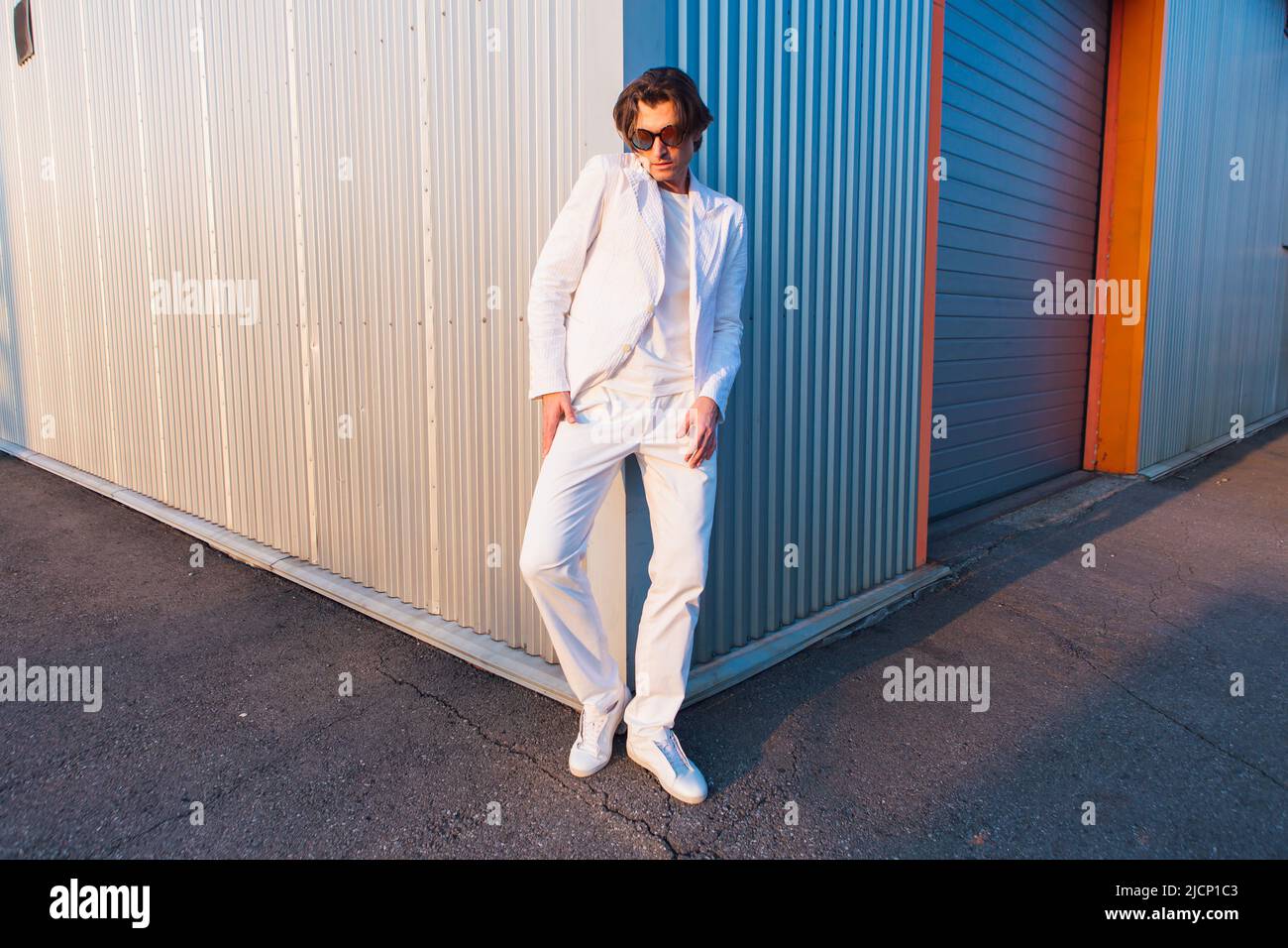 Portrait of a handsome man dressed in a white suit and round hippie ...