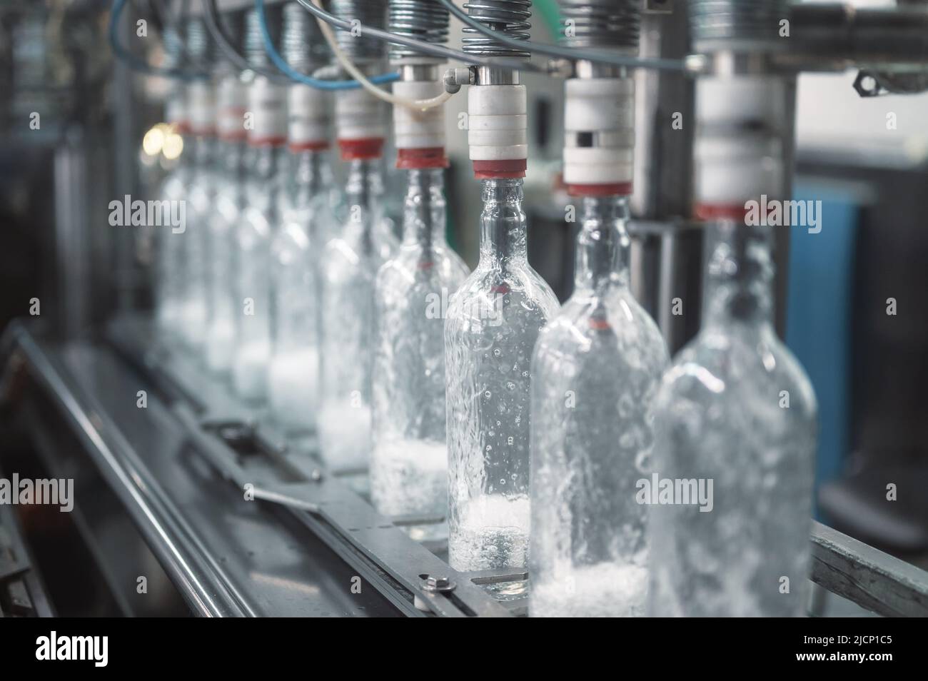 Equipment pours vodka into glass bottles on production line Stock Photo ...
