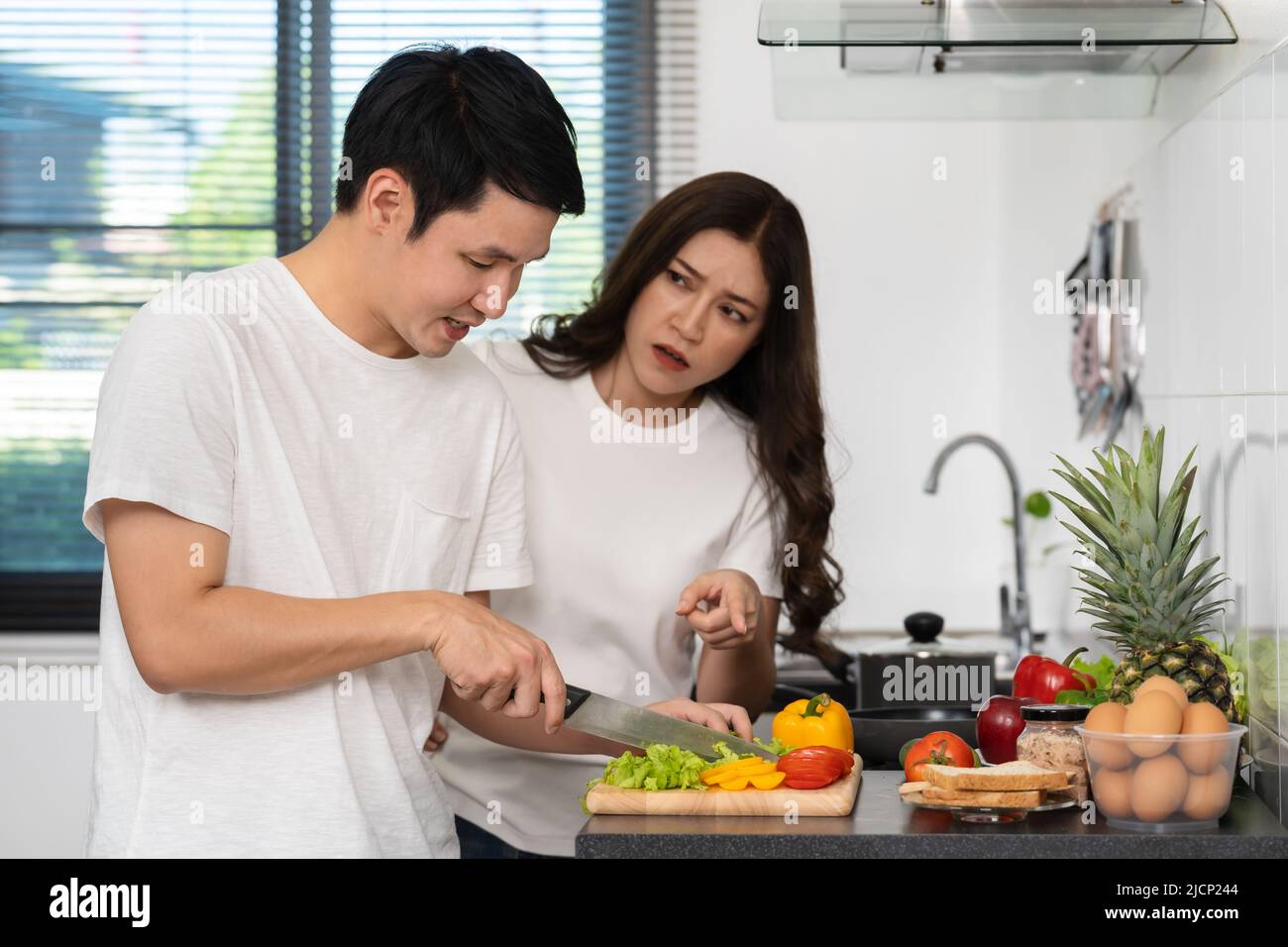 tired couple cooking and preparing vegetables in the kitchen at home ...