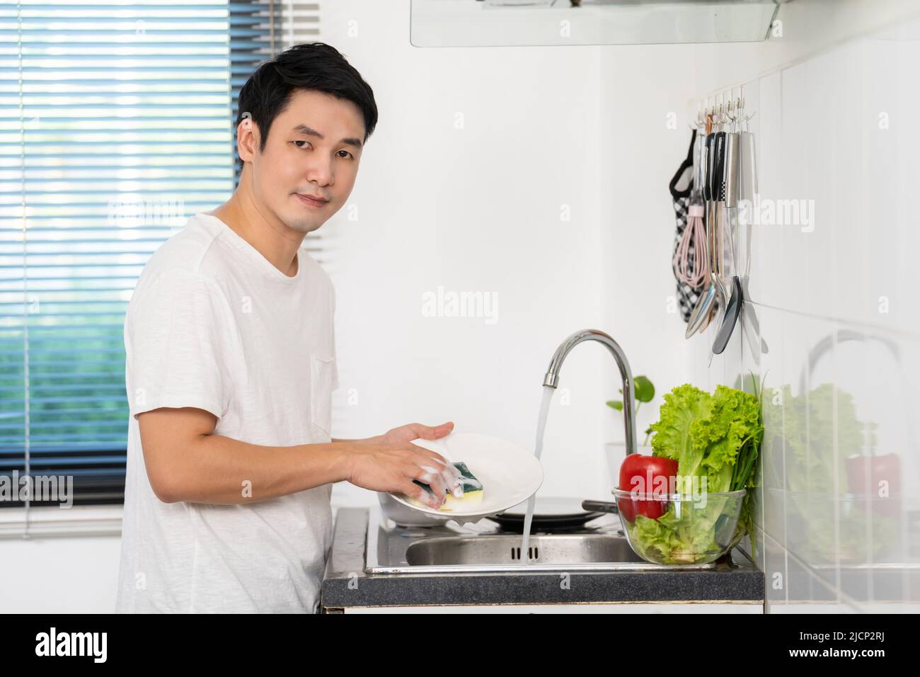 happy young man washing dishes in the sink in the kitchen at home Stock ...