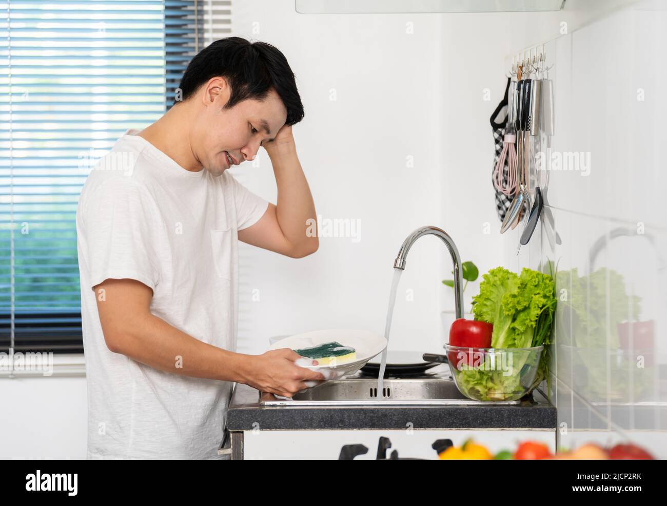 tired man washing dishes in the sink in the kitchen at home Stock Photo ...