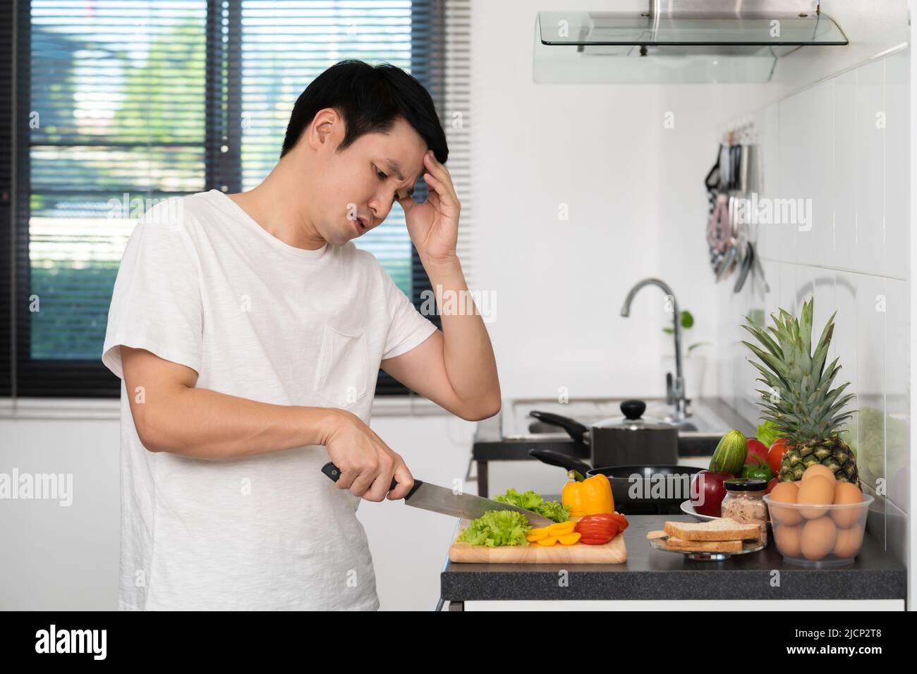 tired man with preparing vegetables to cooking in the kitchen at home ...