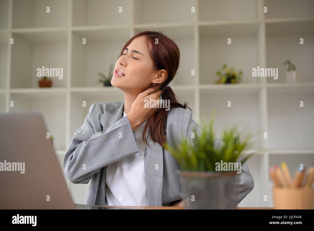 Millennial Asian businesswoman tired from work, suffering from neck ...