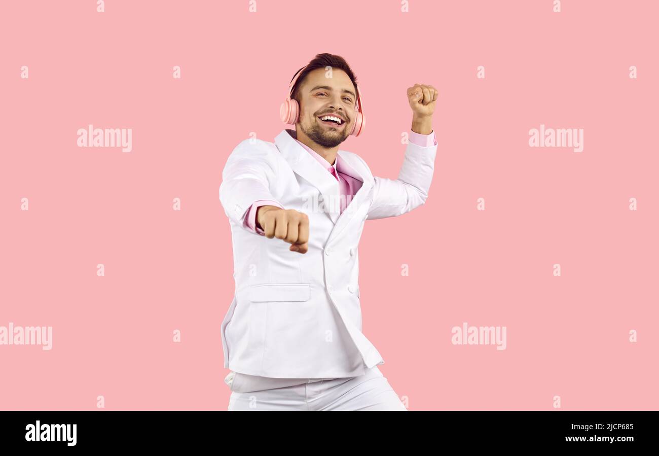Funny man in suit having fun listening to music in wireless headphones ...