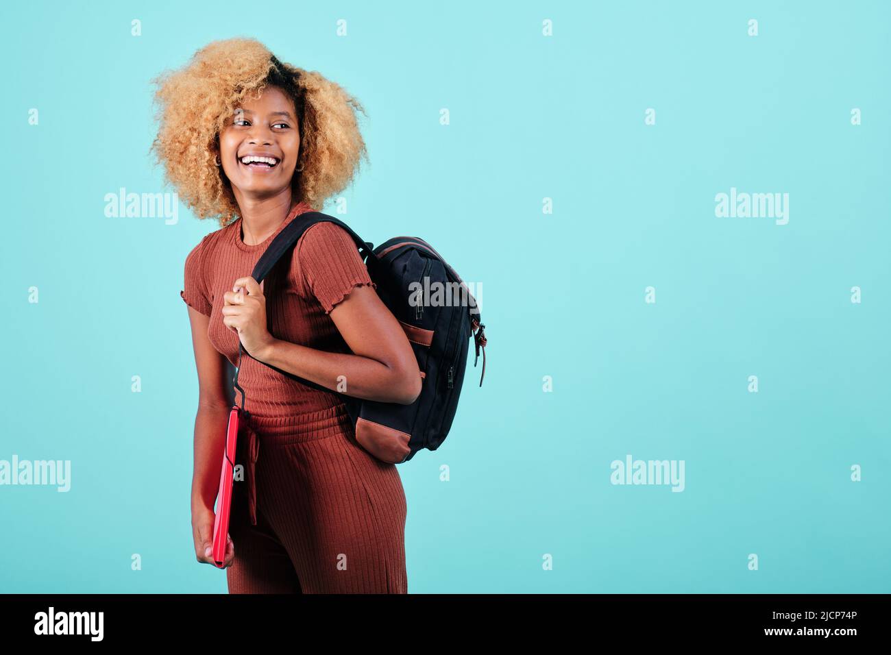 Happy afro student looking away and smiling while standing on an ...
