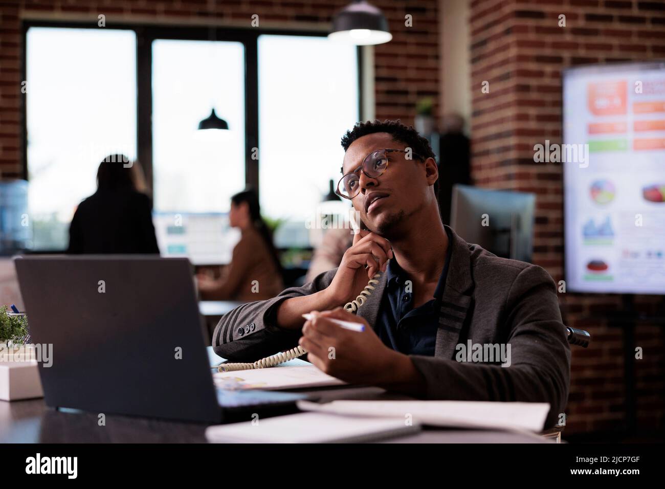 Male secretary wheelchair user answering landline phone call, having ...