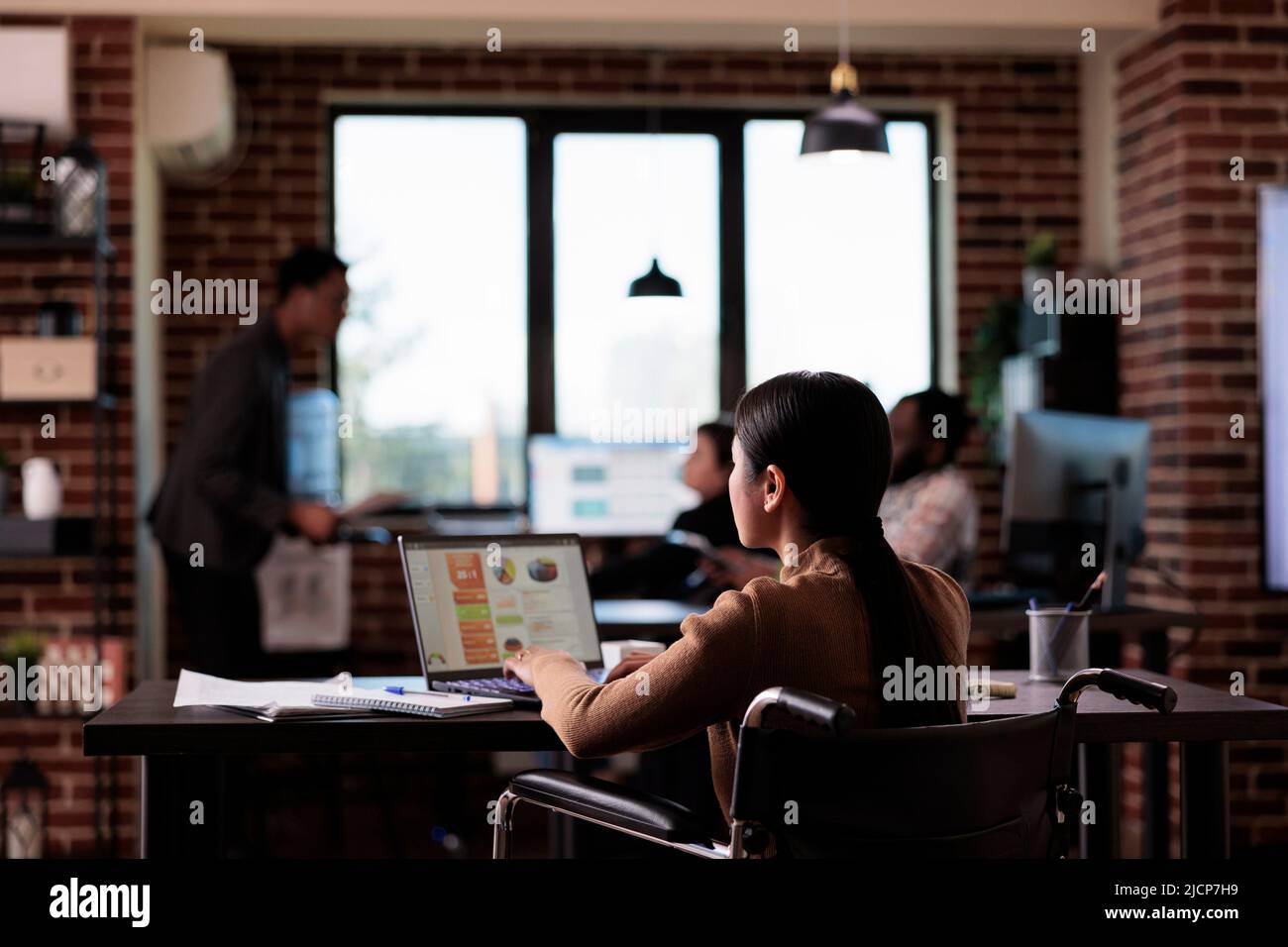 Businesswoman living with disability analyzing report on laptop ...