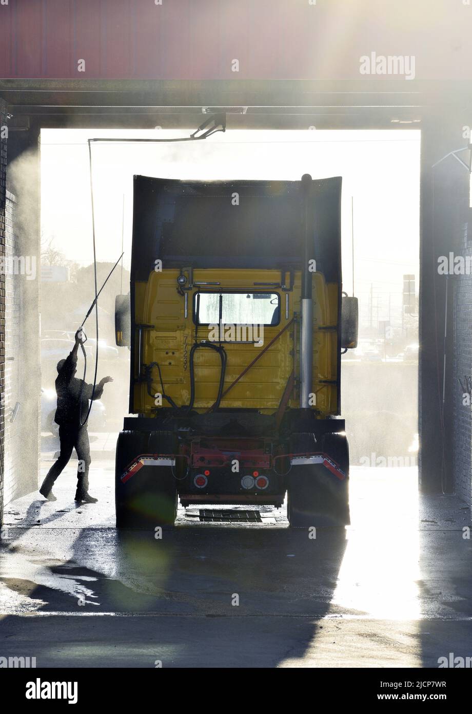 Man washing a semi-truck cab in the early morning at a truck wash in ...